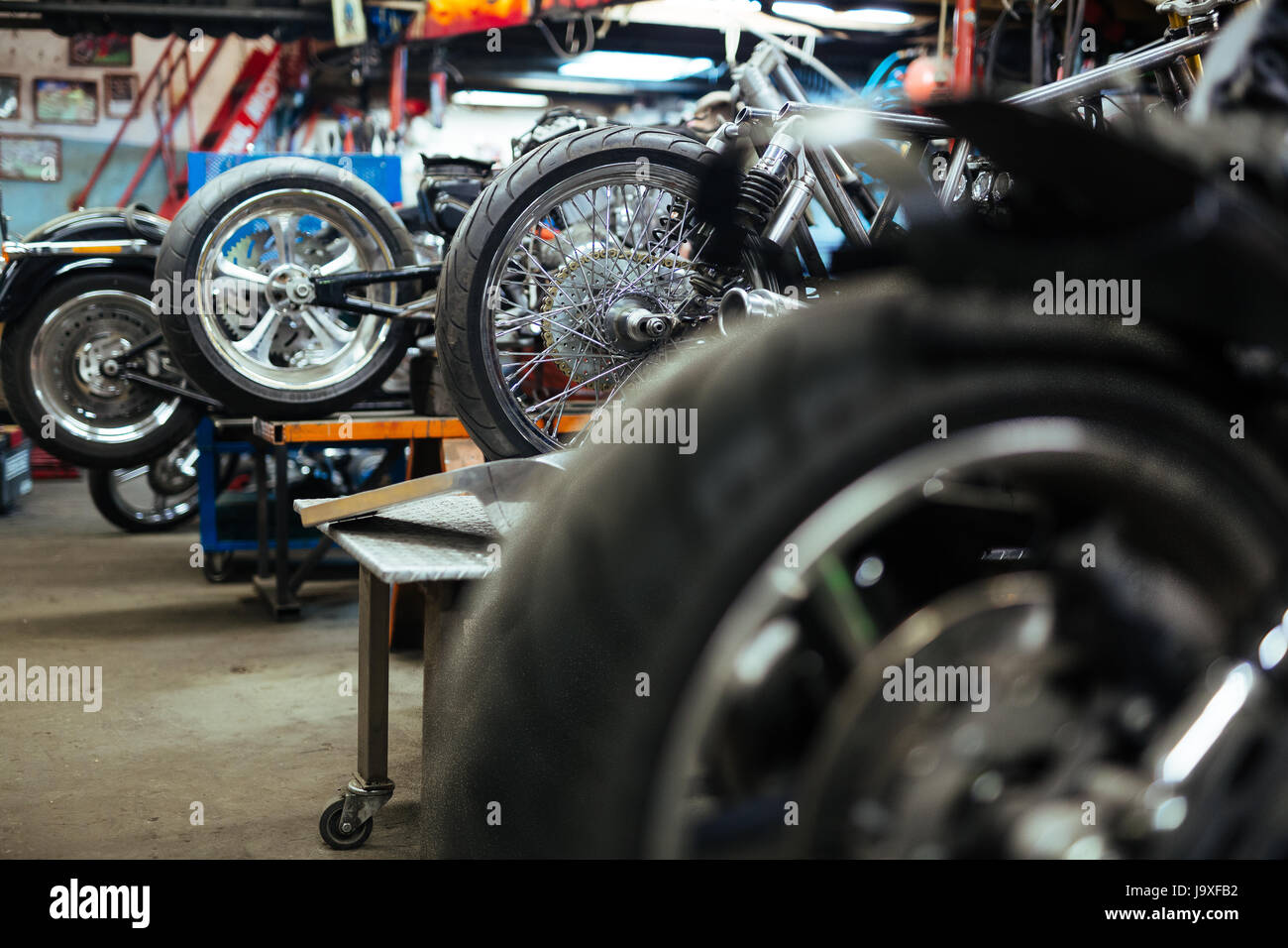Background image of several motorcycles on stands in repair shop with ...