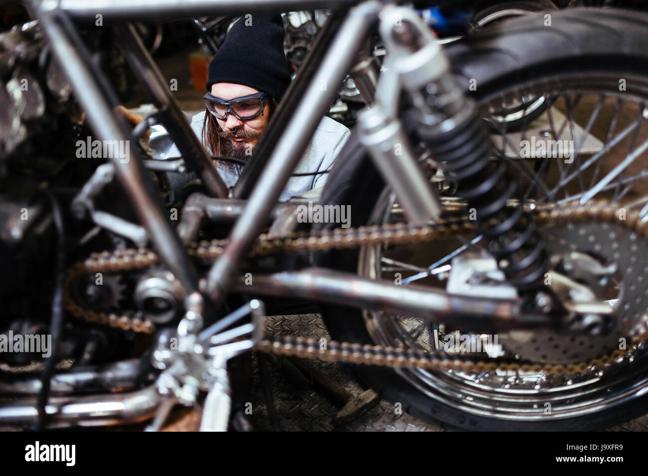 Portrait of brutal bearded man assembling custom motorcycle in garage ...