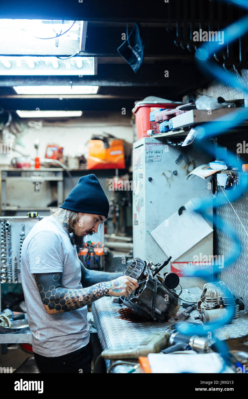Side view portrait of modern tattooed man fixing broken engine in ...