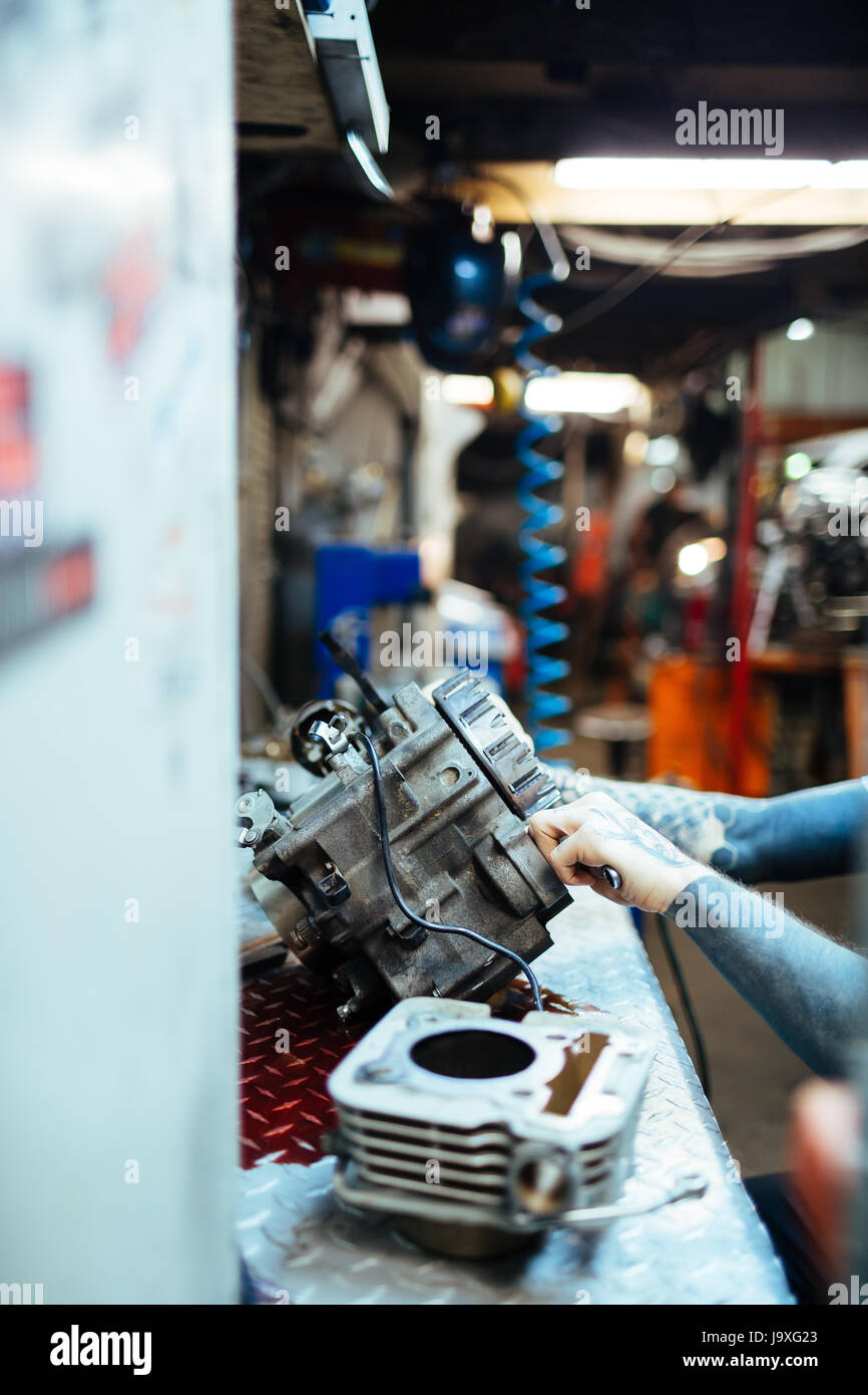 Closeup portrait of modern tattooed mechanic fixing broken parts at ...