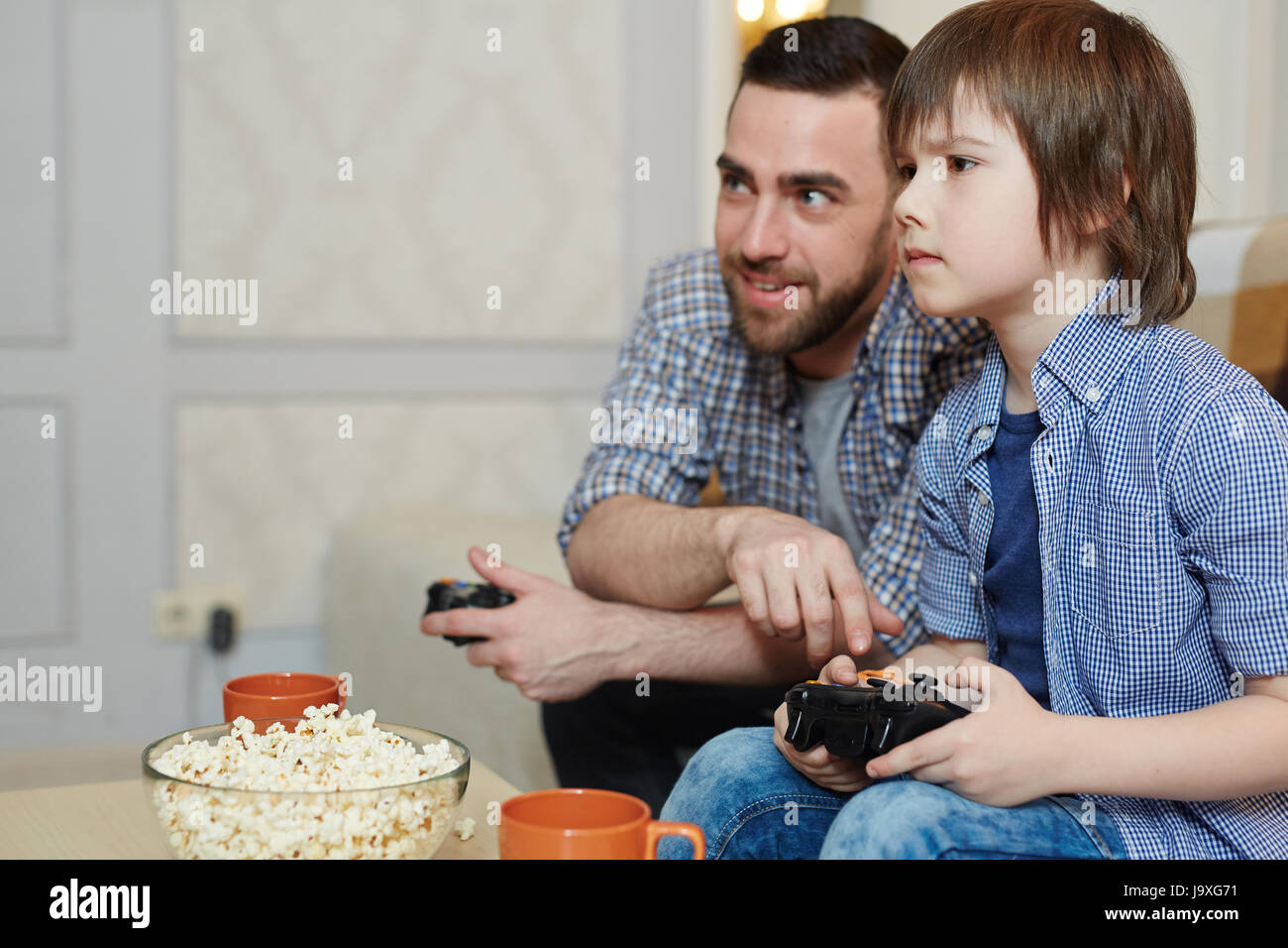 Young man playing video game with his son Stock Photo - Alamy
