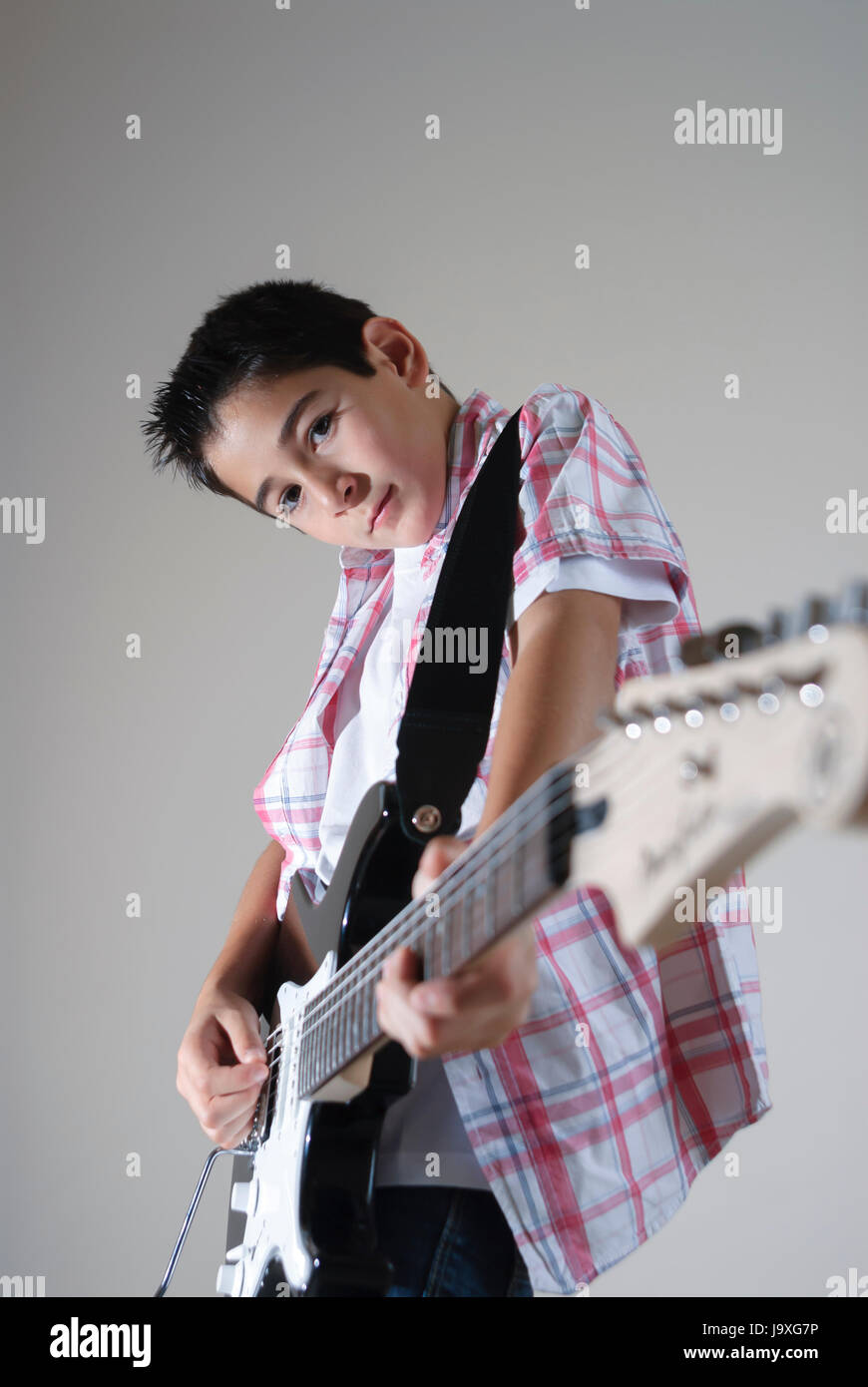 Teen boy playing electric guitar isolated over withe gray background ...