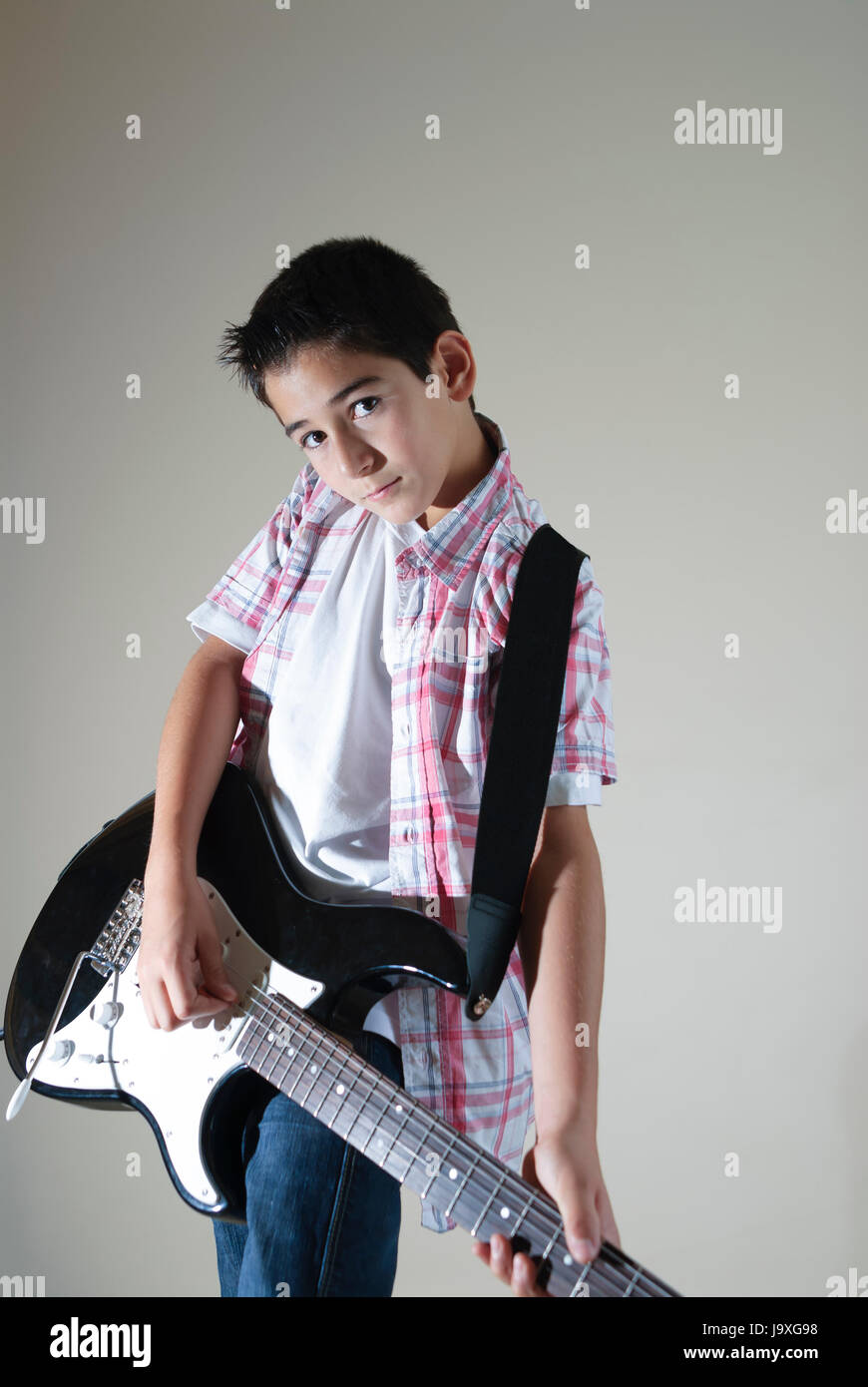 Teen boy playing electric guitar isolated over withe gray background ...