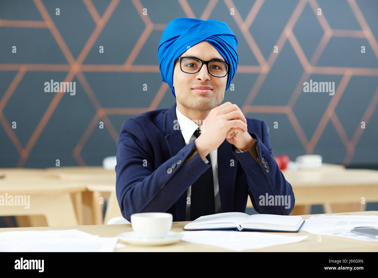 Young businessman in blue turban and suit sitting by workplace Stock ...
