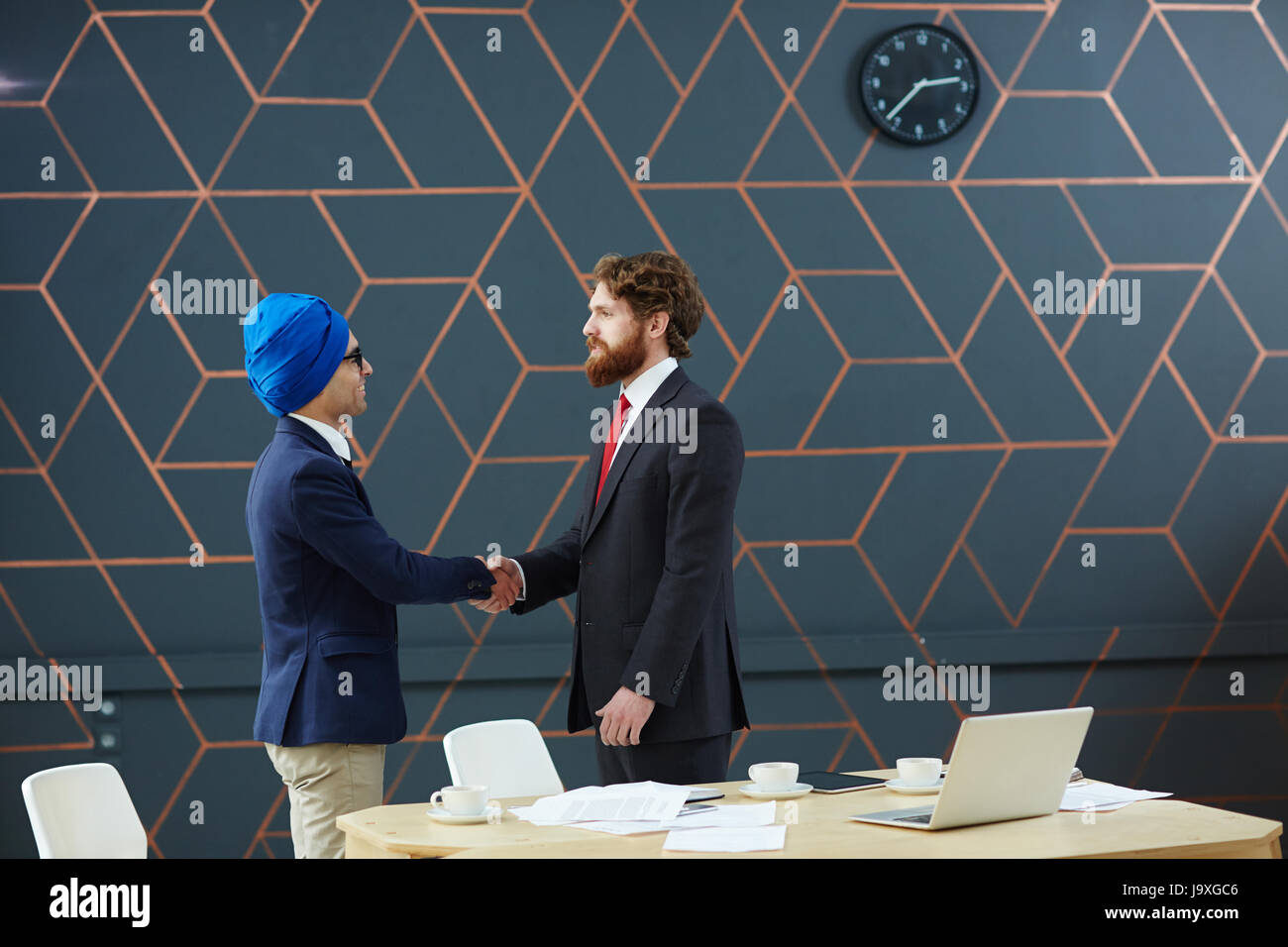 Intercultural men handshaking by workplace Stock Photo - Alamy