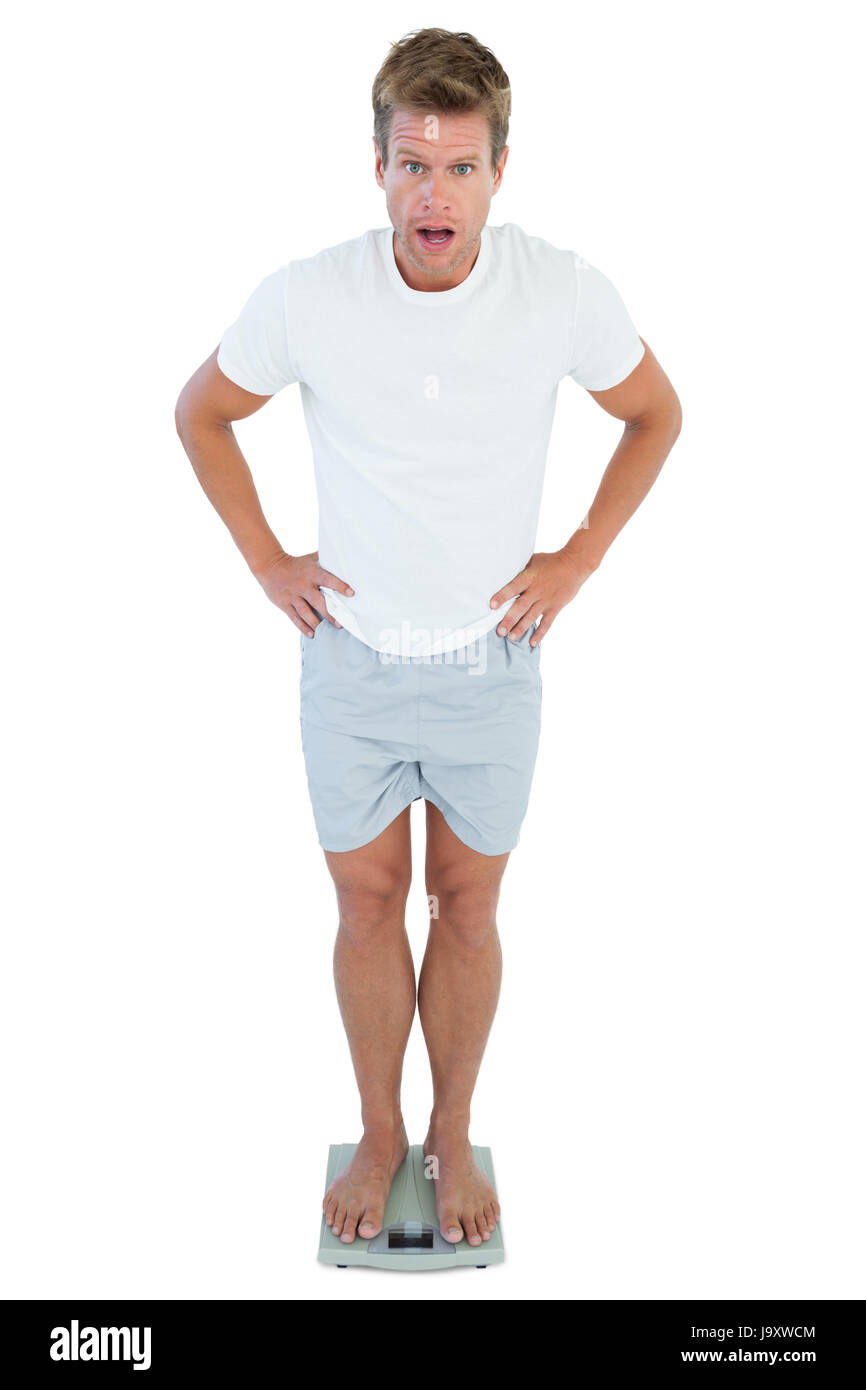 Shocked man standing on a weighing scale on white background Stock ...