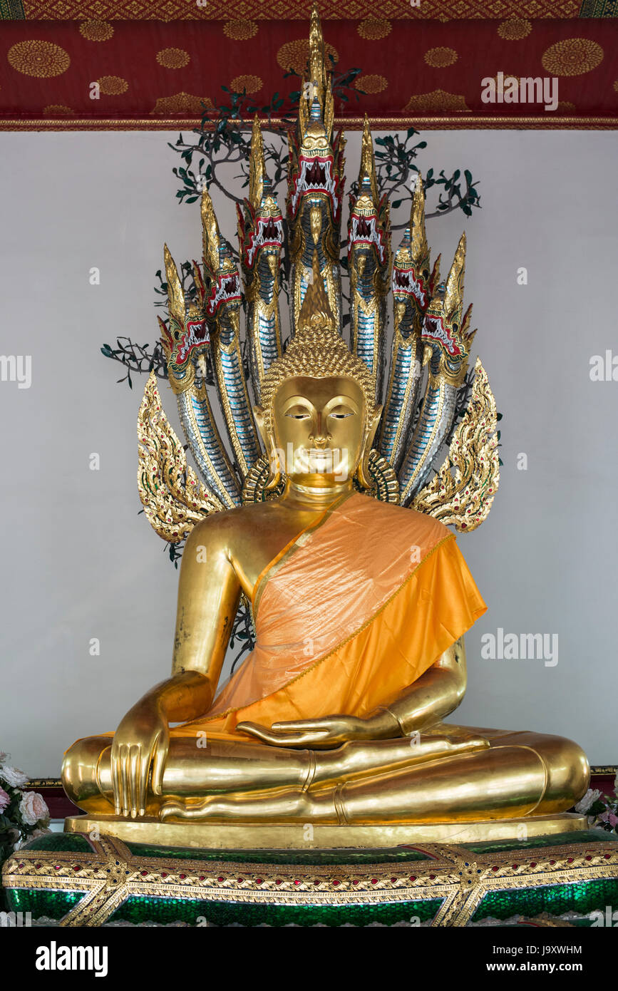 A gold coloured statue of the Buddha sits in a shrine at Wat Pho ...