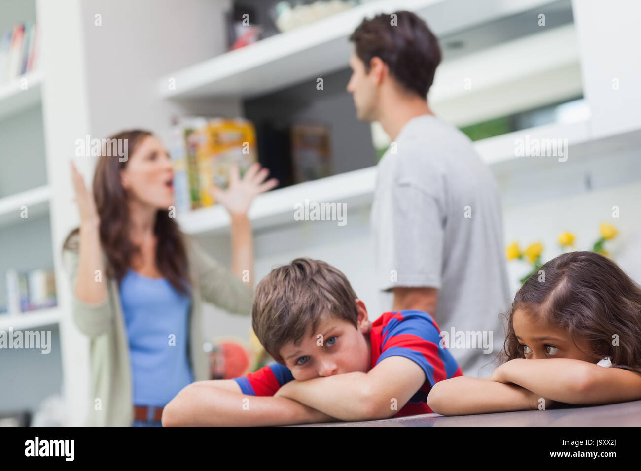 Couple arguing behind their children in the kitchen Stock Photo - Alamy