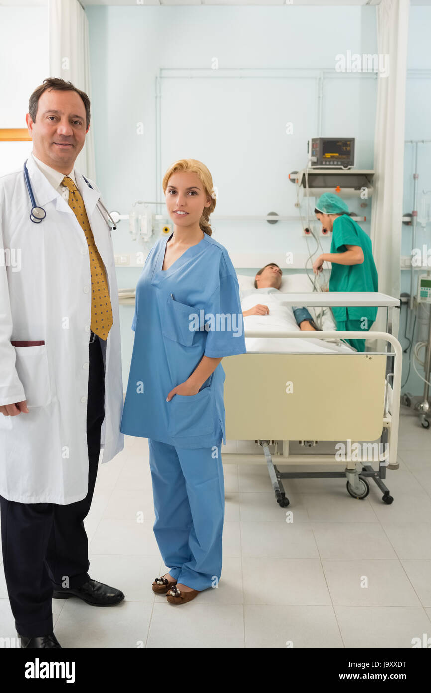 Doctor and nurse standing in a hospital room where patients are resting ...