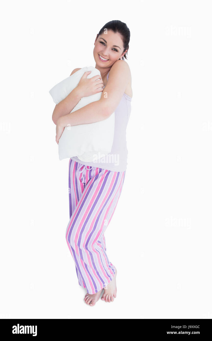 Smiling woman holding a pillow in her arms and standing Stock Photo - Alamy
