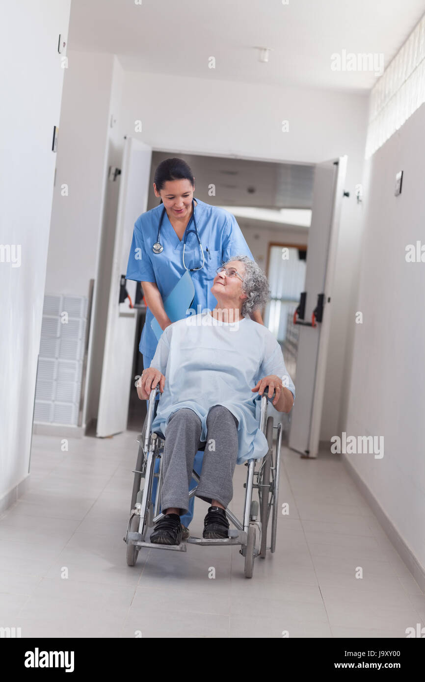 Nurse pushing a patient in a wheelchair in hospital ward Stock Photo ...