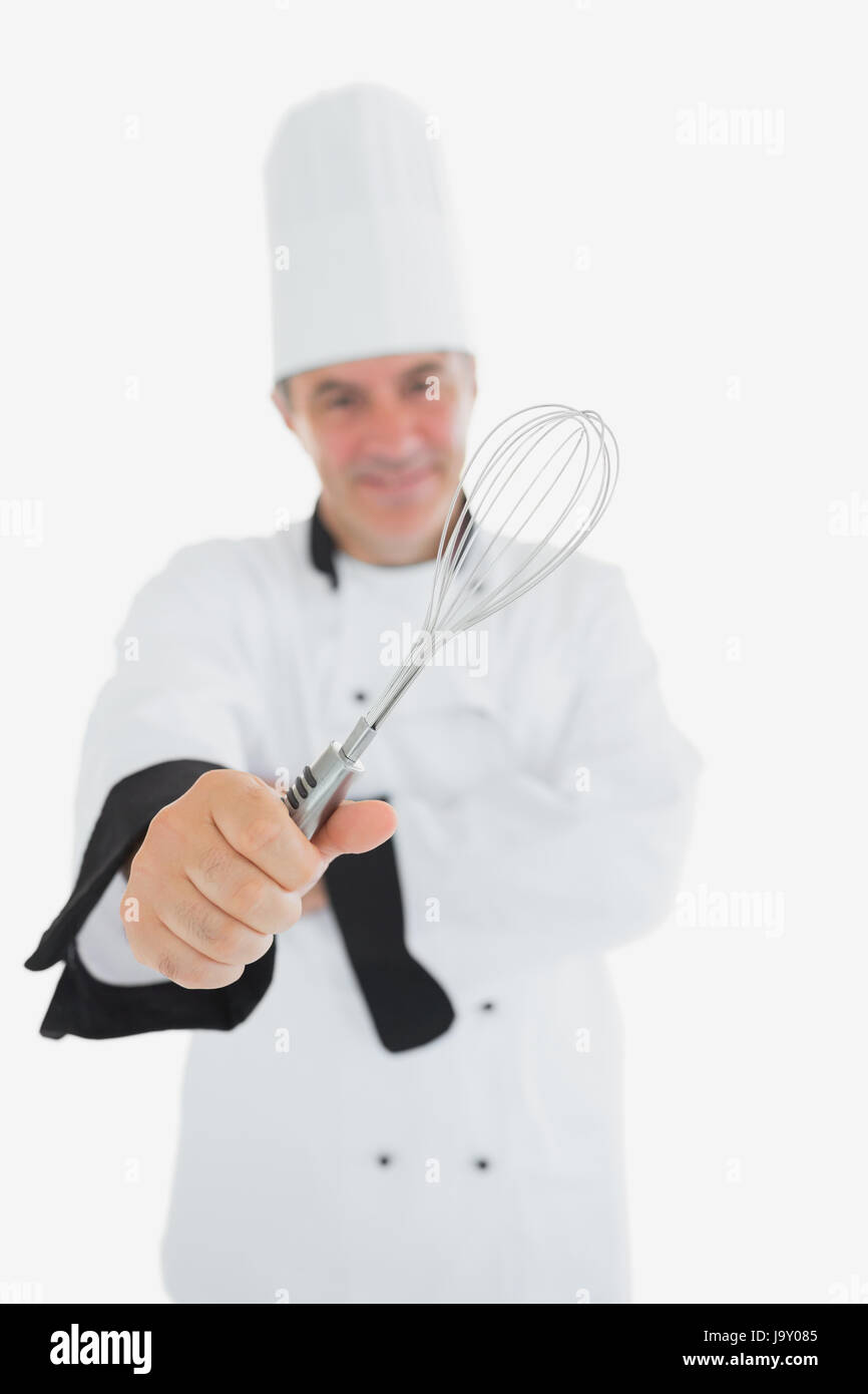 Portrait of male chef showing wire whisk over white background Stock ...