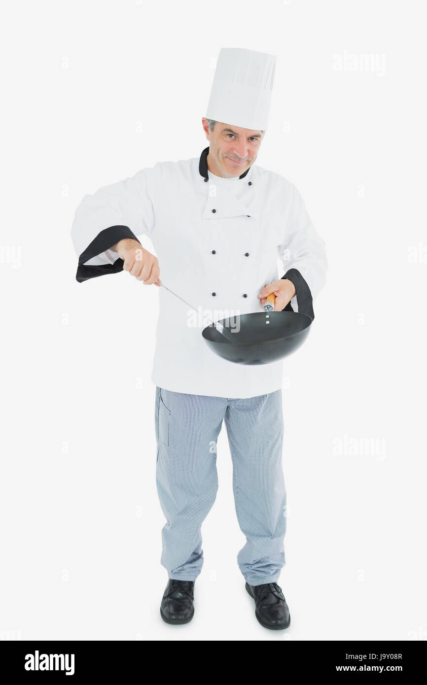 Full length portrait of confident male chef cooking food over white ...