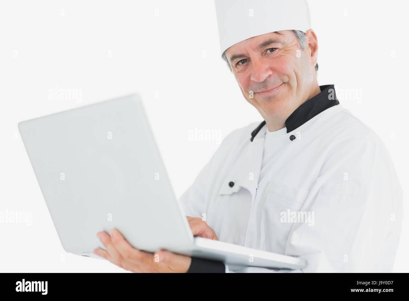 Portrait of male chef using laptop smiling against white background ...