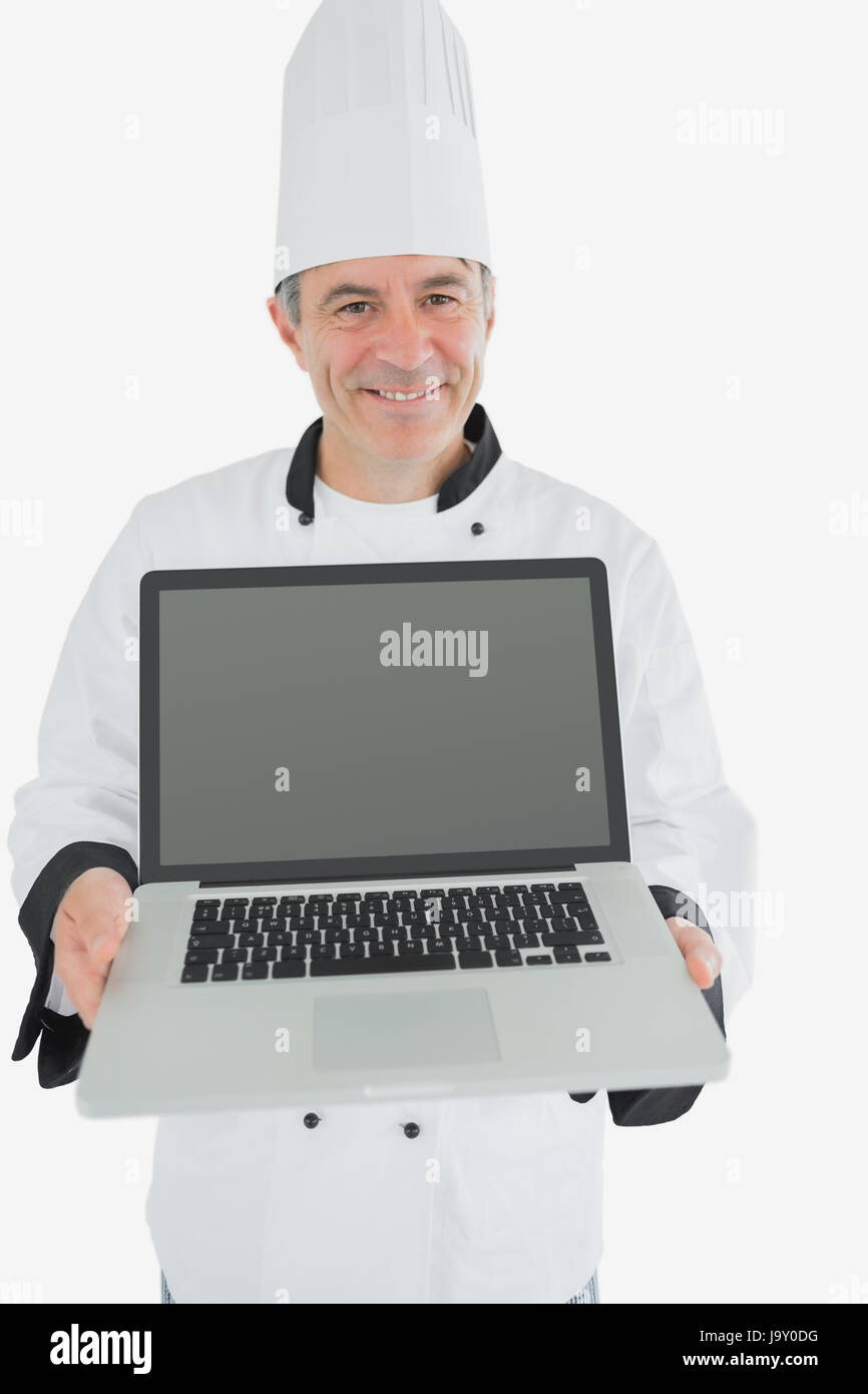 Portrait of happy male chef shwoing laptop against white background ...