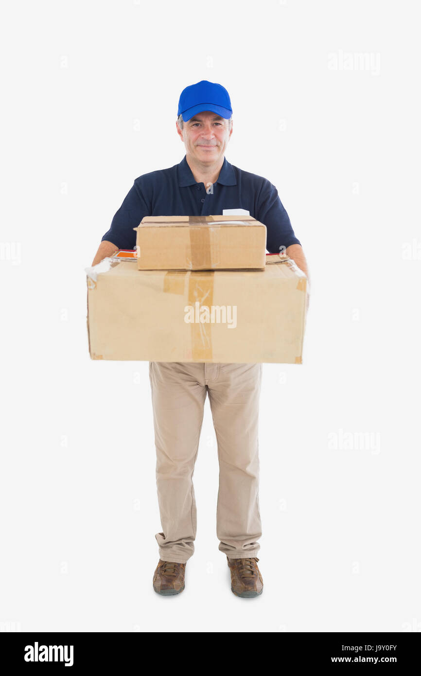Portrait of delivery man carrying stack of cardboard packages against ...