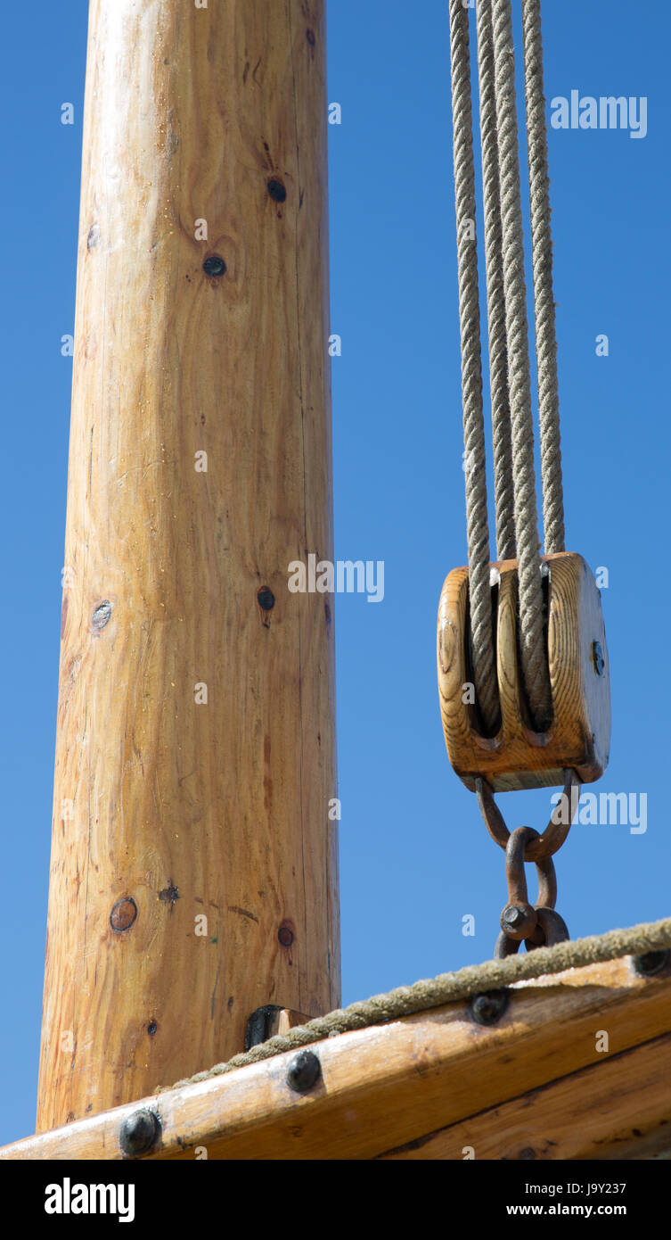 Mast, with pulley, block and tackle against blue sky on an old sailing ...