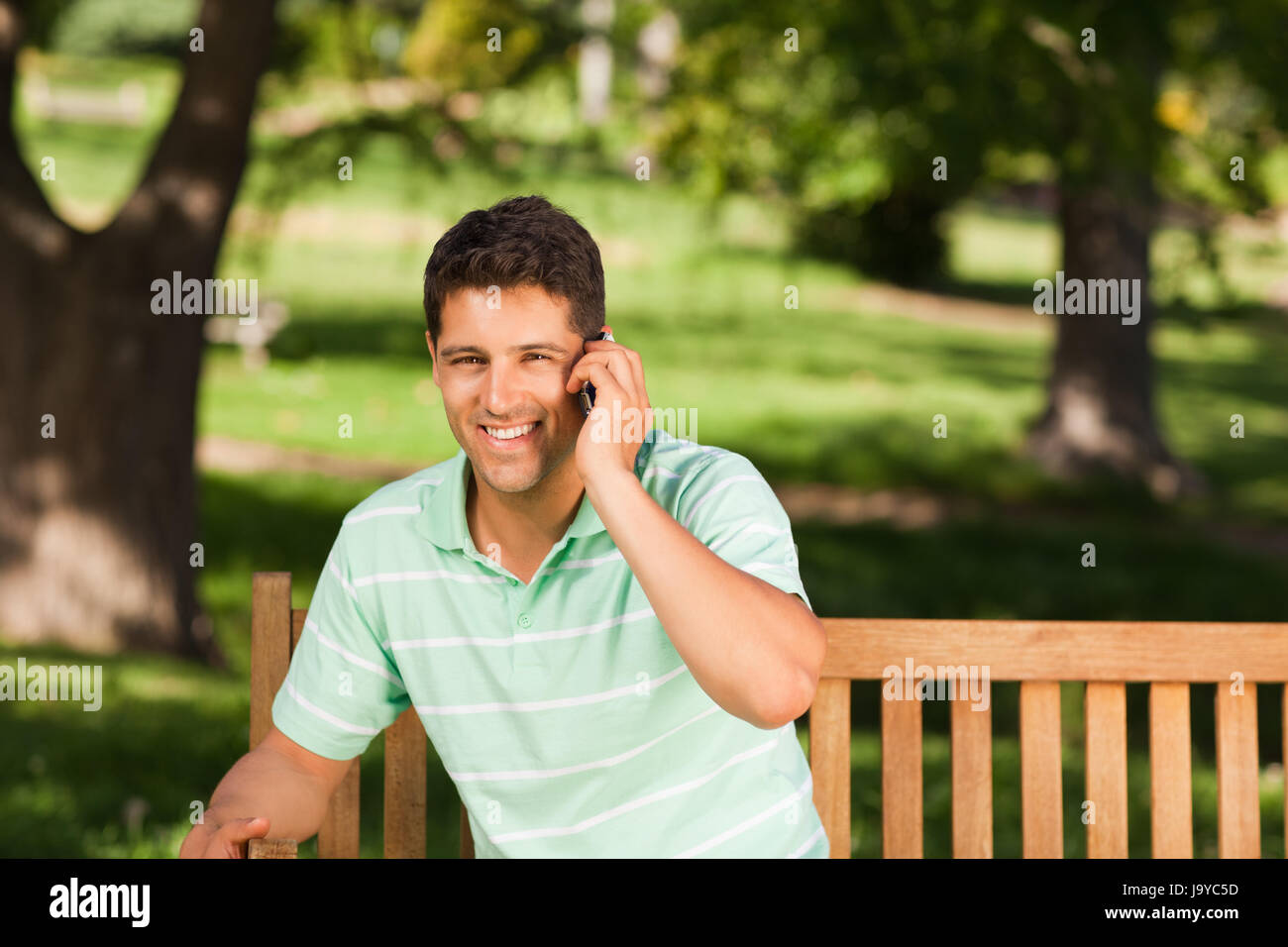 Young handsome man phoning in a park Stock Photo - Alamy