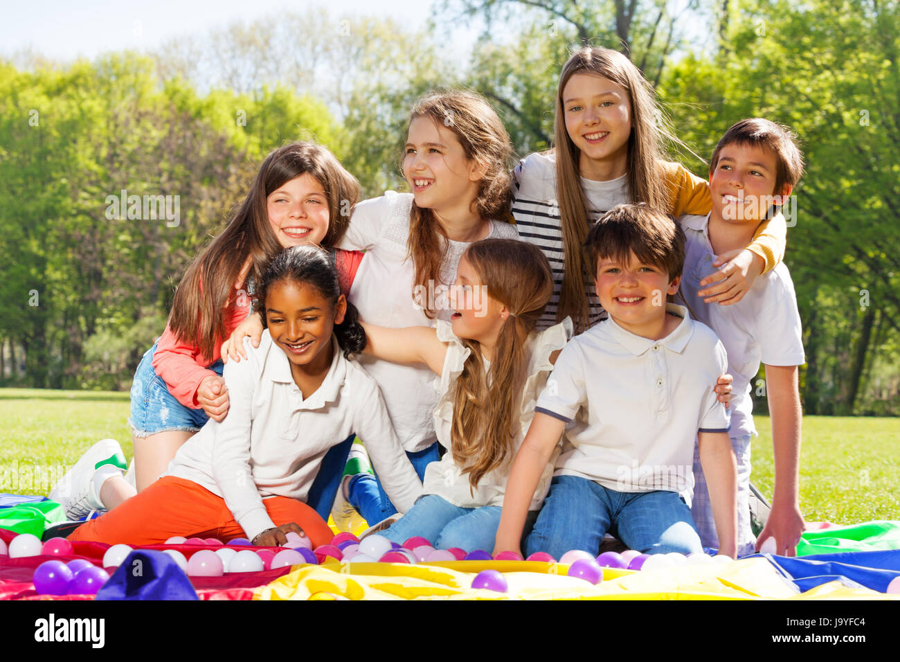 Happy kids having fun sitting on grass in the park Stock Photo - Alamy