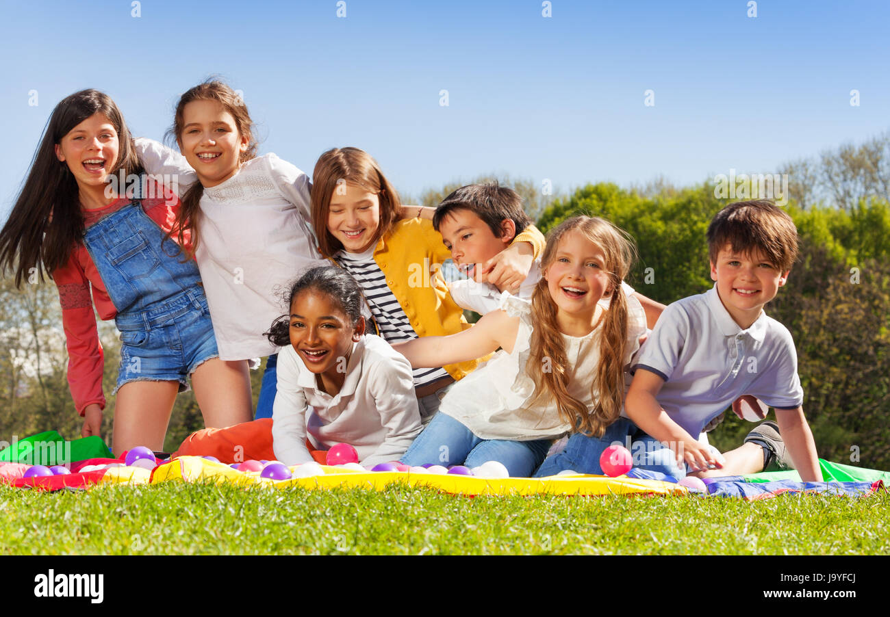 Happy kids having fun sitting on the lawn in park Stock Photo - Alamy