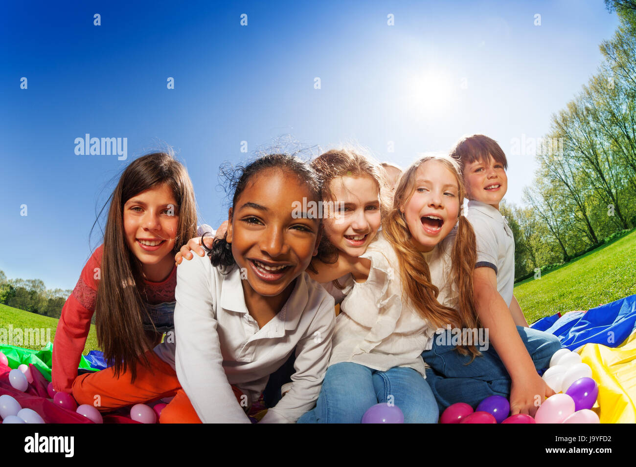 Kids sitting on mat surrounded by colorful balls Stock Photo - Alamy