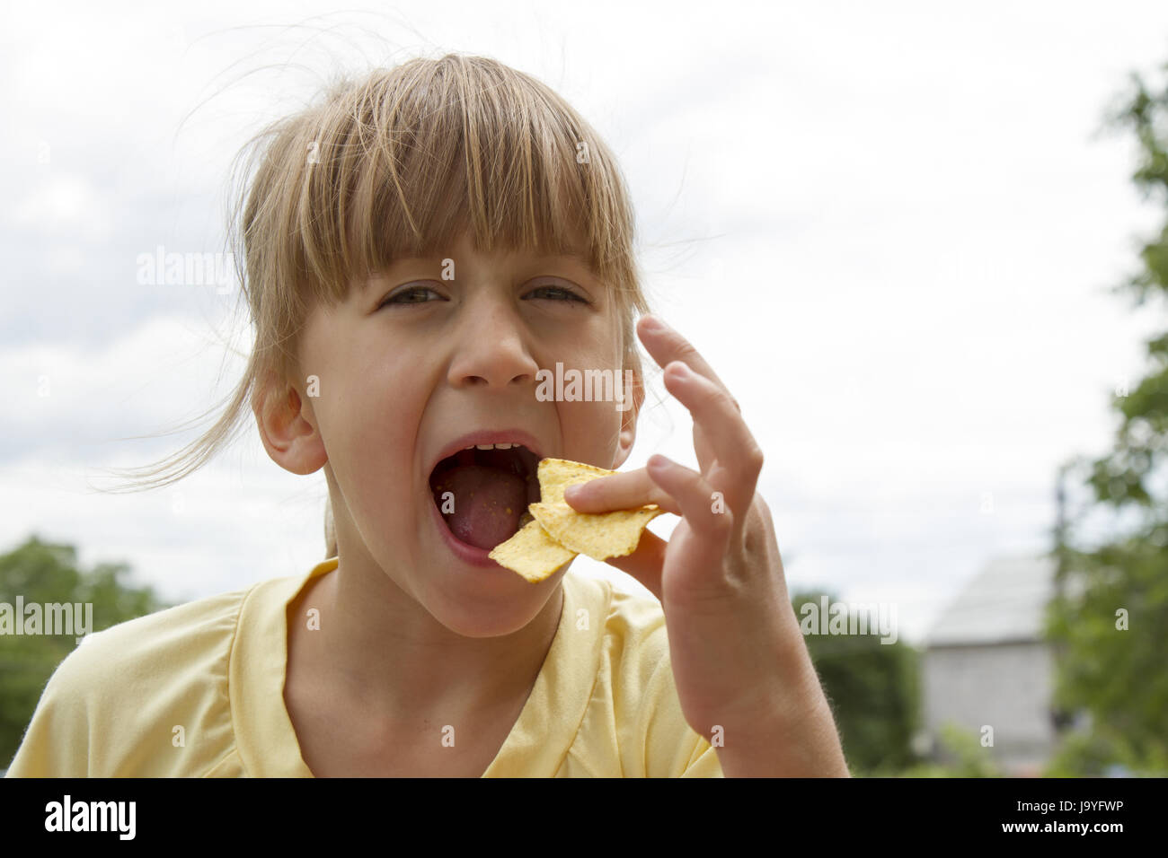 A cute little girl eating chips outdoor Stock Photo - Alamy