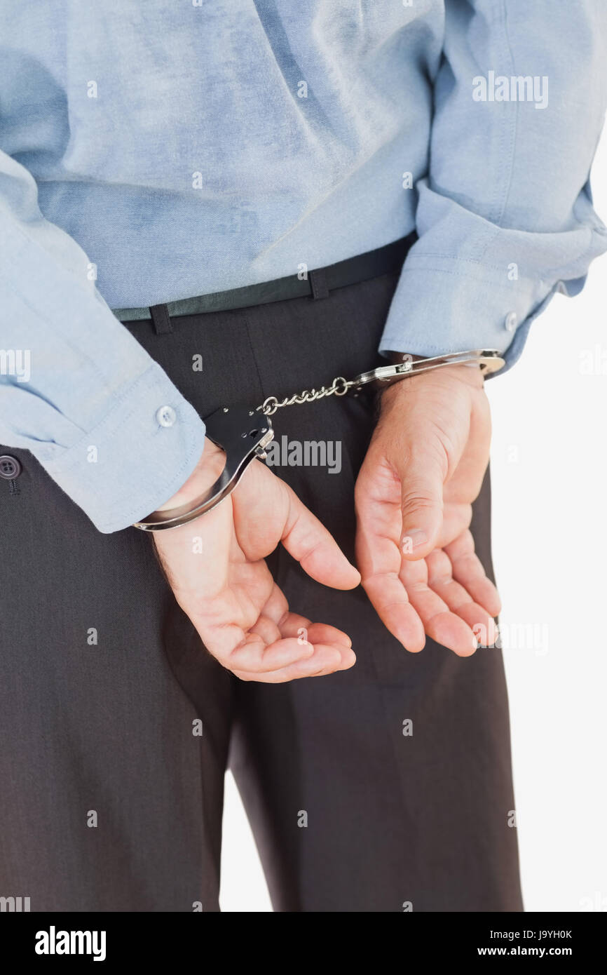 Rear view of businessman in handcuffs standing isolated over white ...
