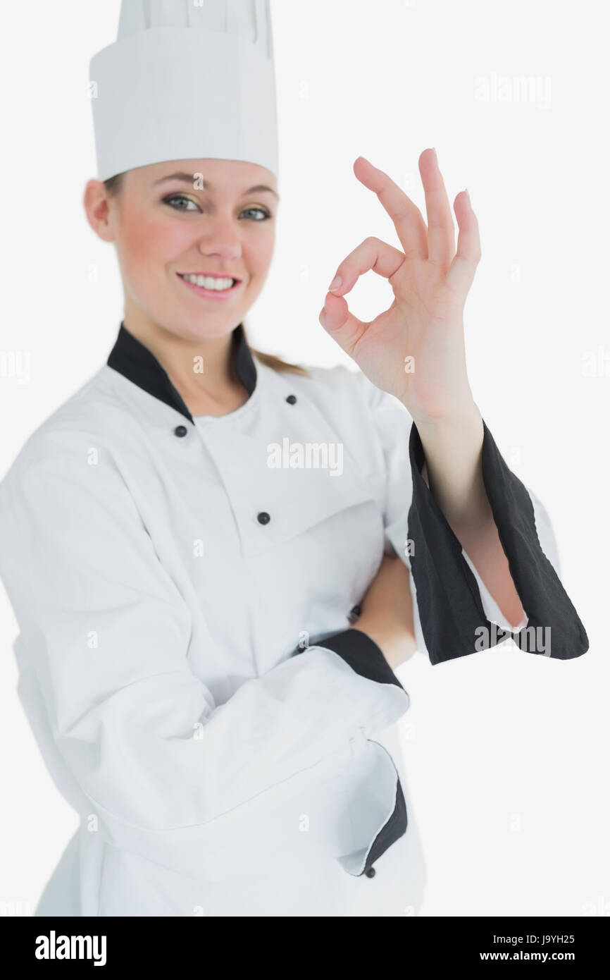 Portrait of happy female chef showing ok sign over white background ...