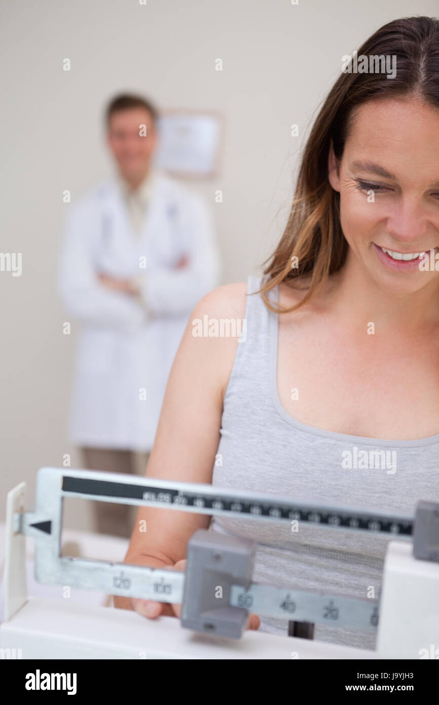 Woman weighing herself being supervised by doctor Stock Photo - Alamy