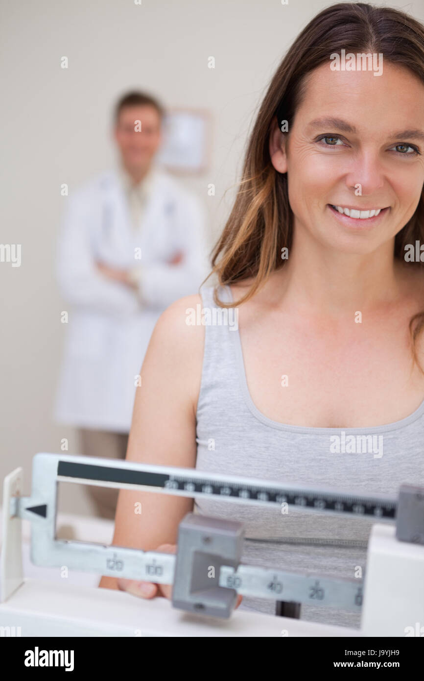Smiling woman on the scale being supervised by doctor Stock Photo - Alamy