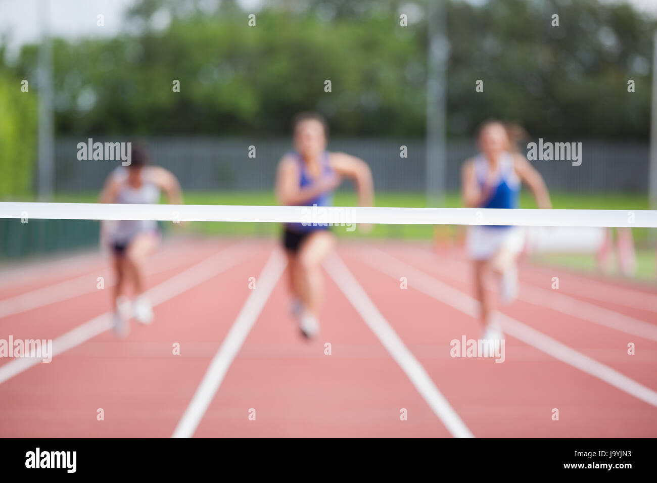 Female athletes running towards finish line on track field Stock Photo ...