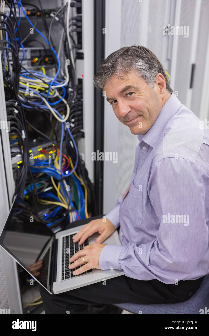 Man typing on laptop while doing server maintenance in data center and ...