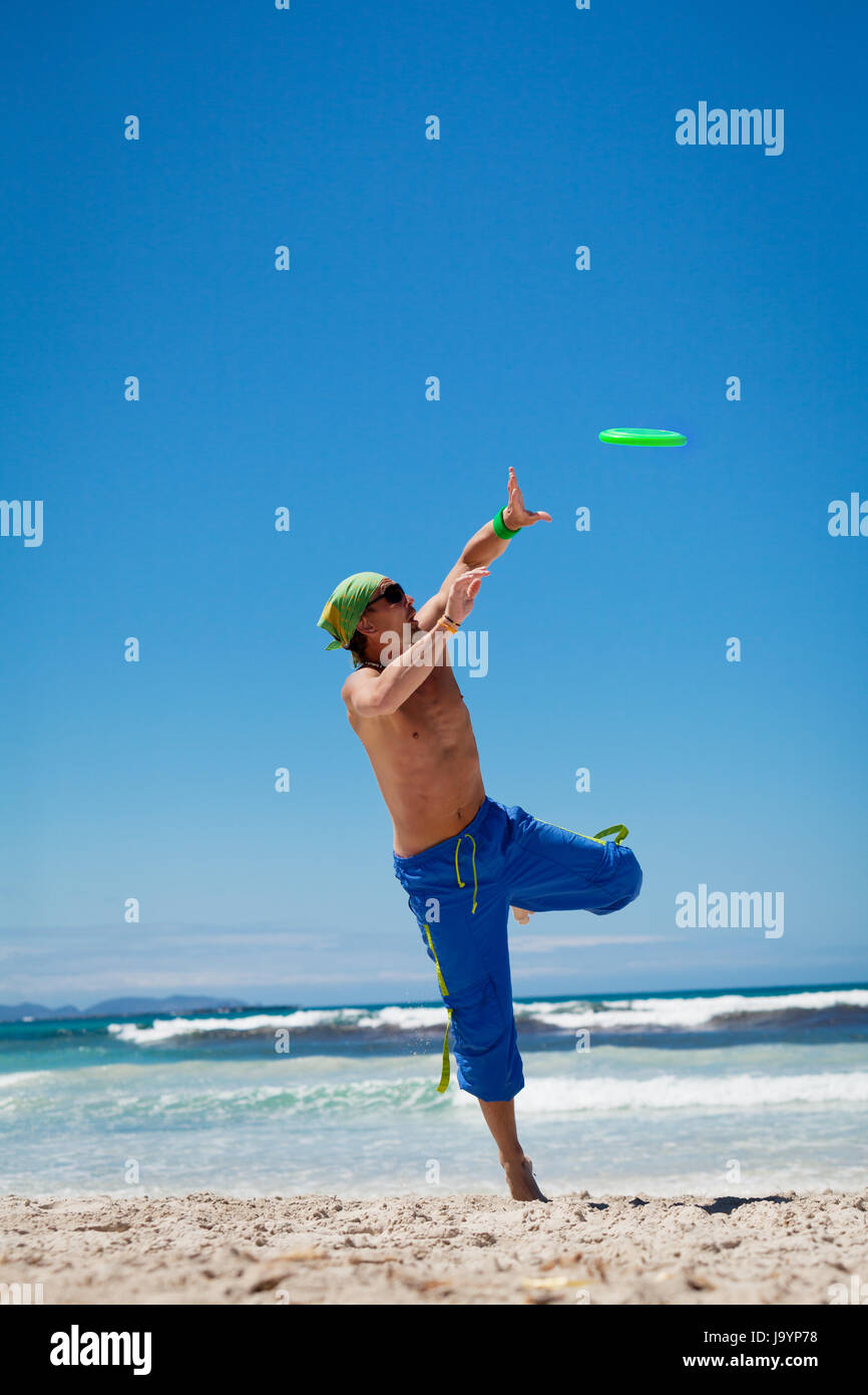 sporty man playing frisbee on the beach in summer frisby Stock Photo ...