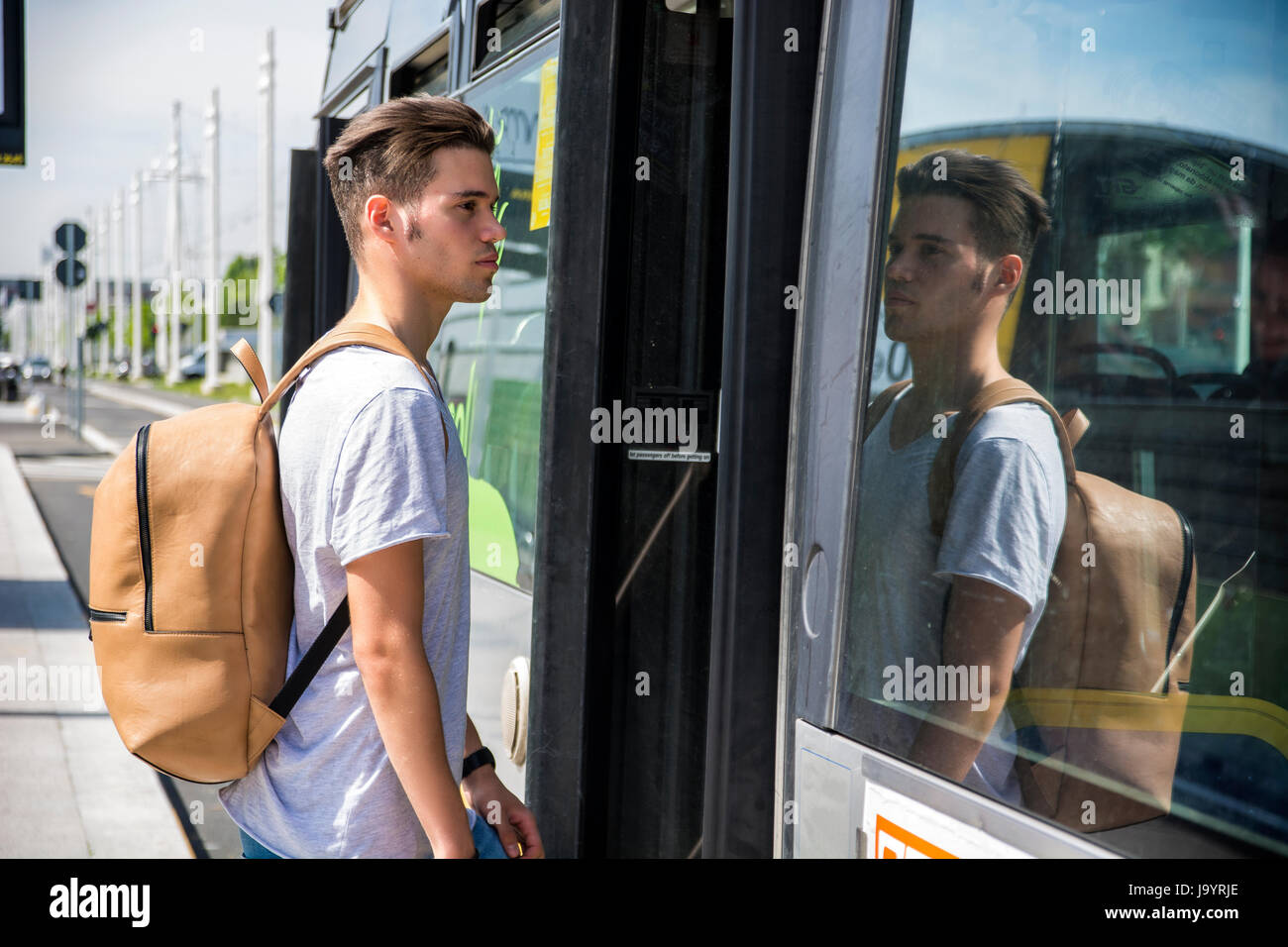 Side view of young casual dressed man with backpack walking into bus ...