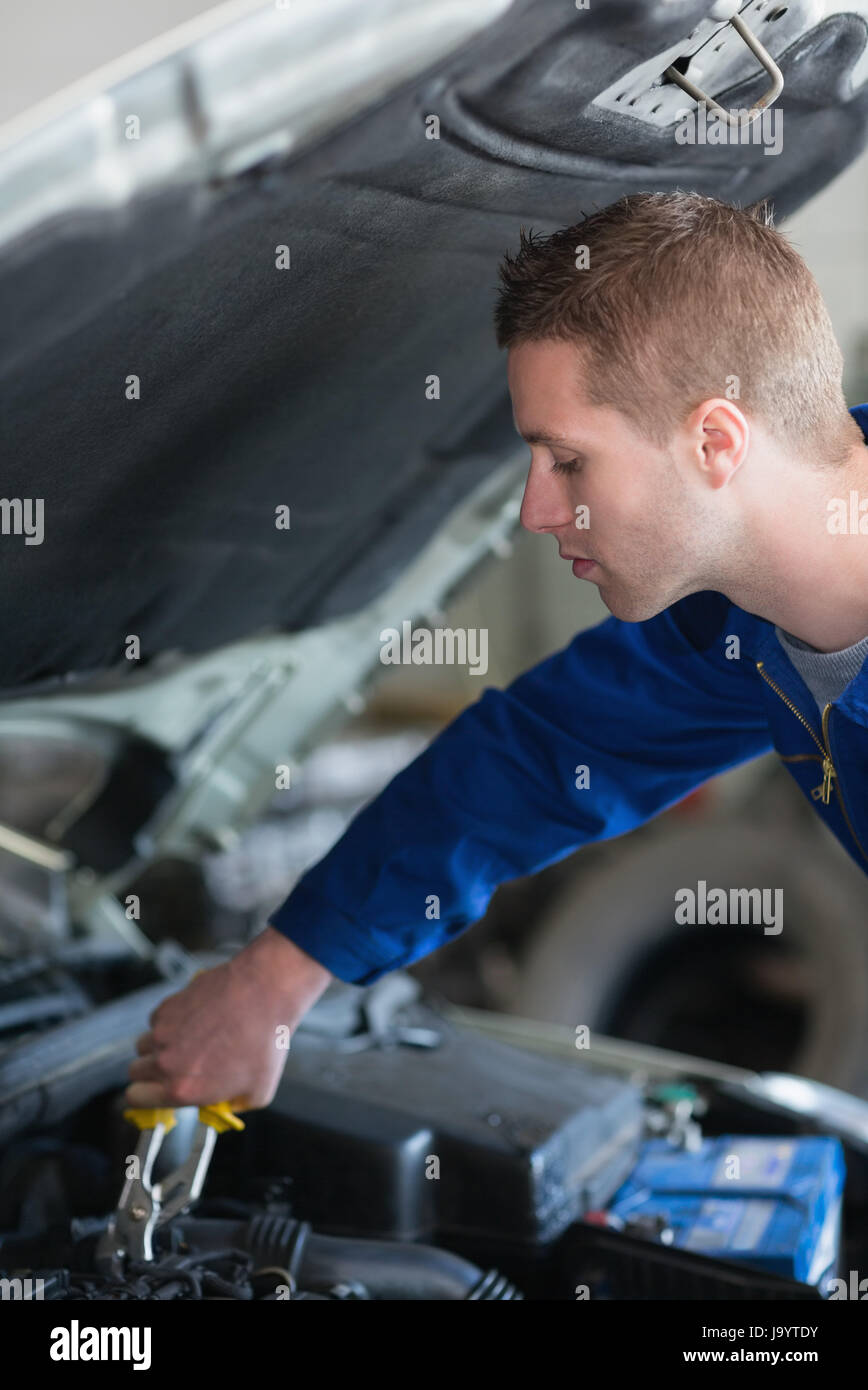 Side view of male car mechanic adjusting engine Stock Photo - Alamy