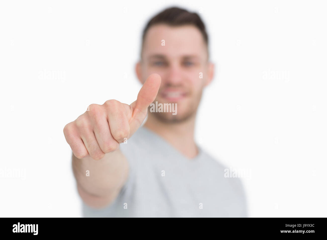 Casual young man gesturing thumbs up over white background Stock Photo ...