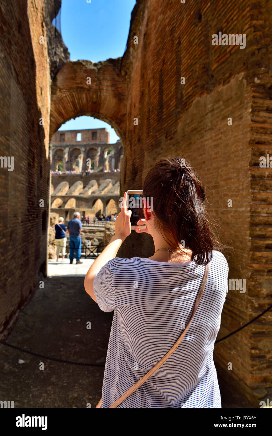 Woman taking a photo with phone camera looking through arch inside of ...