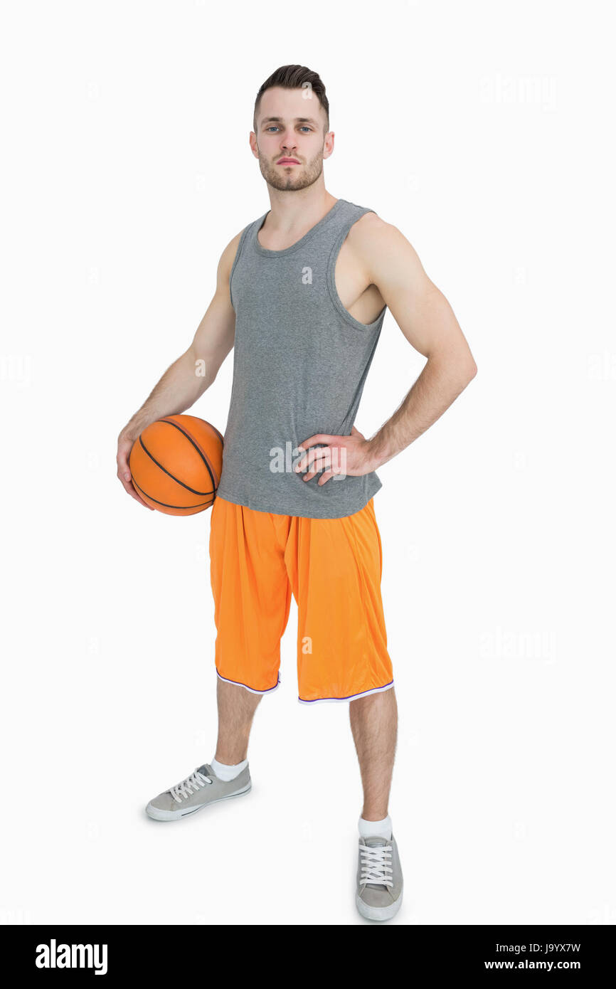 Portrait of young man with basketball standing over white background ...