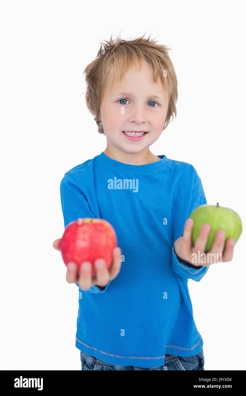 Portrait of young boy holding out green and red apples over white ...