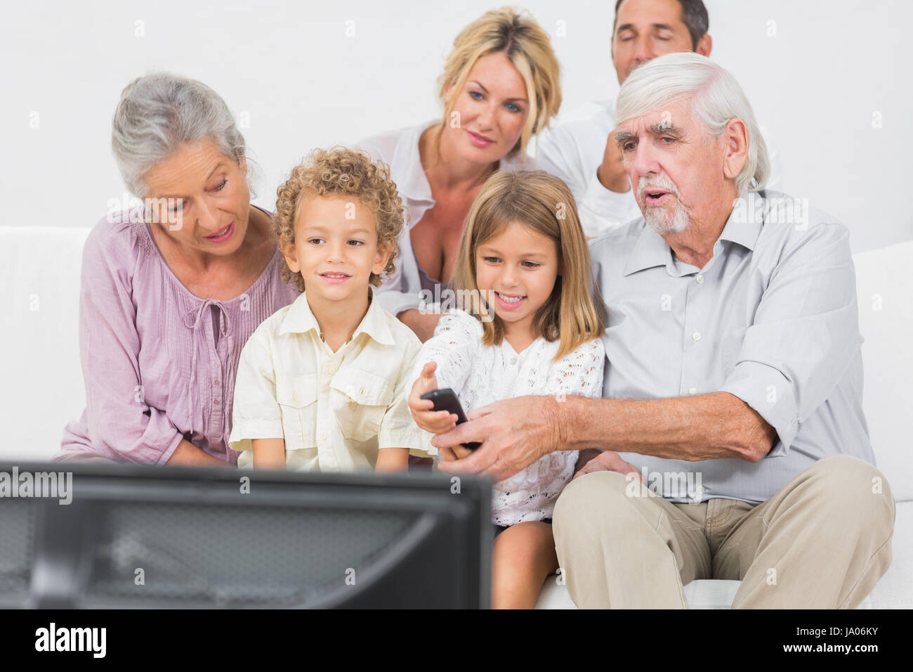 Family watching tv together against a white background Stock Photo - Alamy