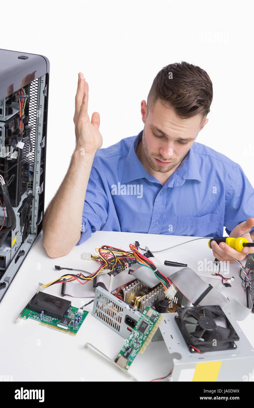 Confused young computer engineer fixing computer parts over white ...