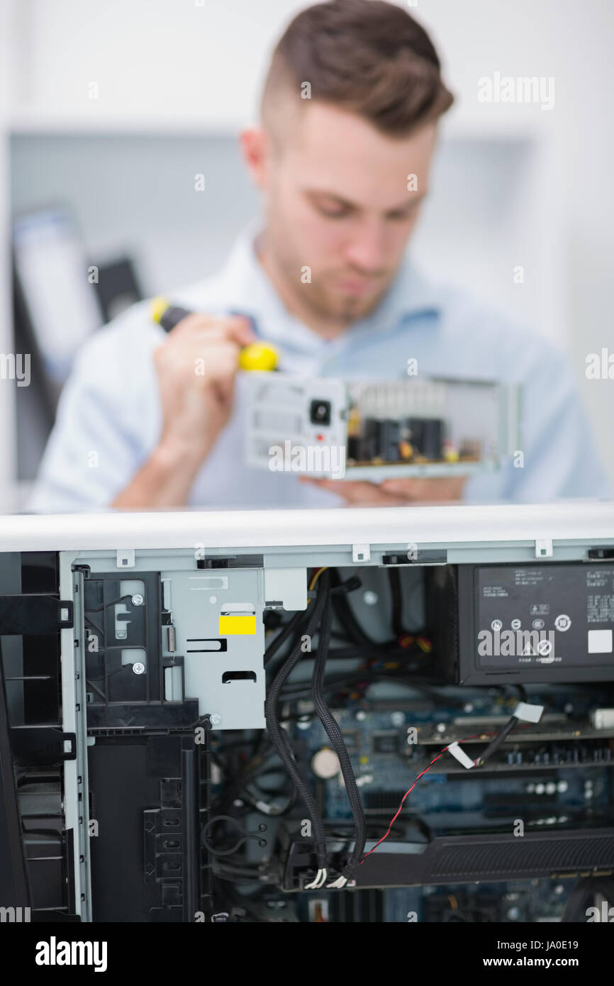 Young computer engineer working on cpu part in front of open cpu at ...