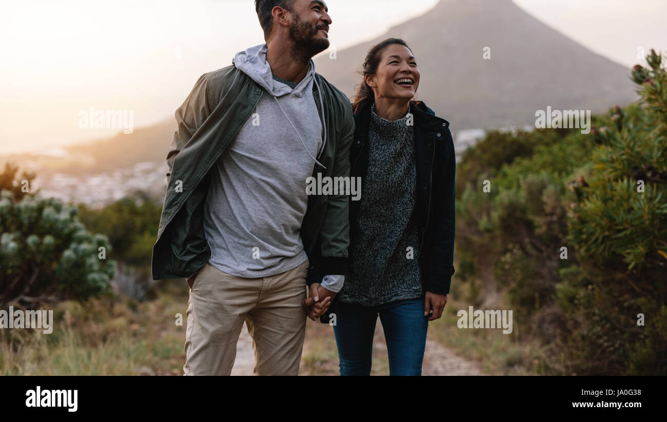 Portrait of smiling young couple walk through country trail. Happy ...