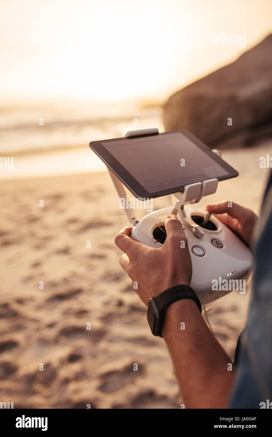 Cropped shot of young man hands holding remote control of a flying ...