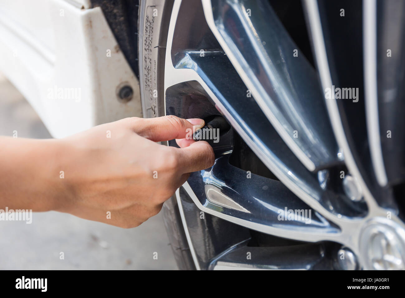Man checking air pressure and filling air in the tires of car. Concept ...