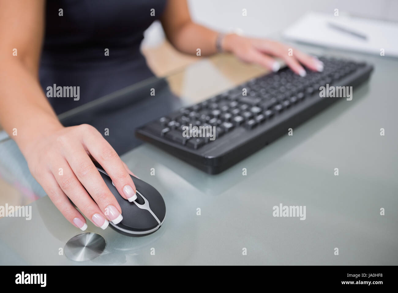 Midsection of woman using computer mouse and keyboard at office desk ...
