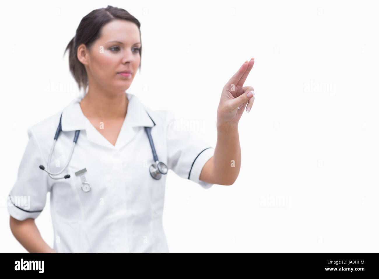Portrait of female nurse pointing at invisible screen against white ...