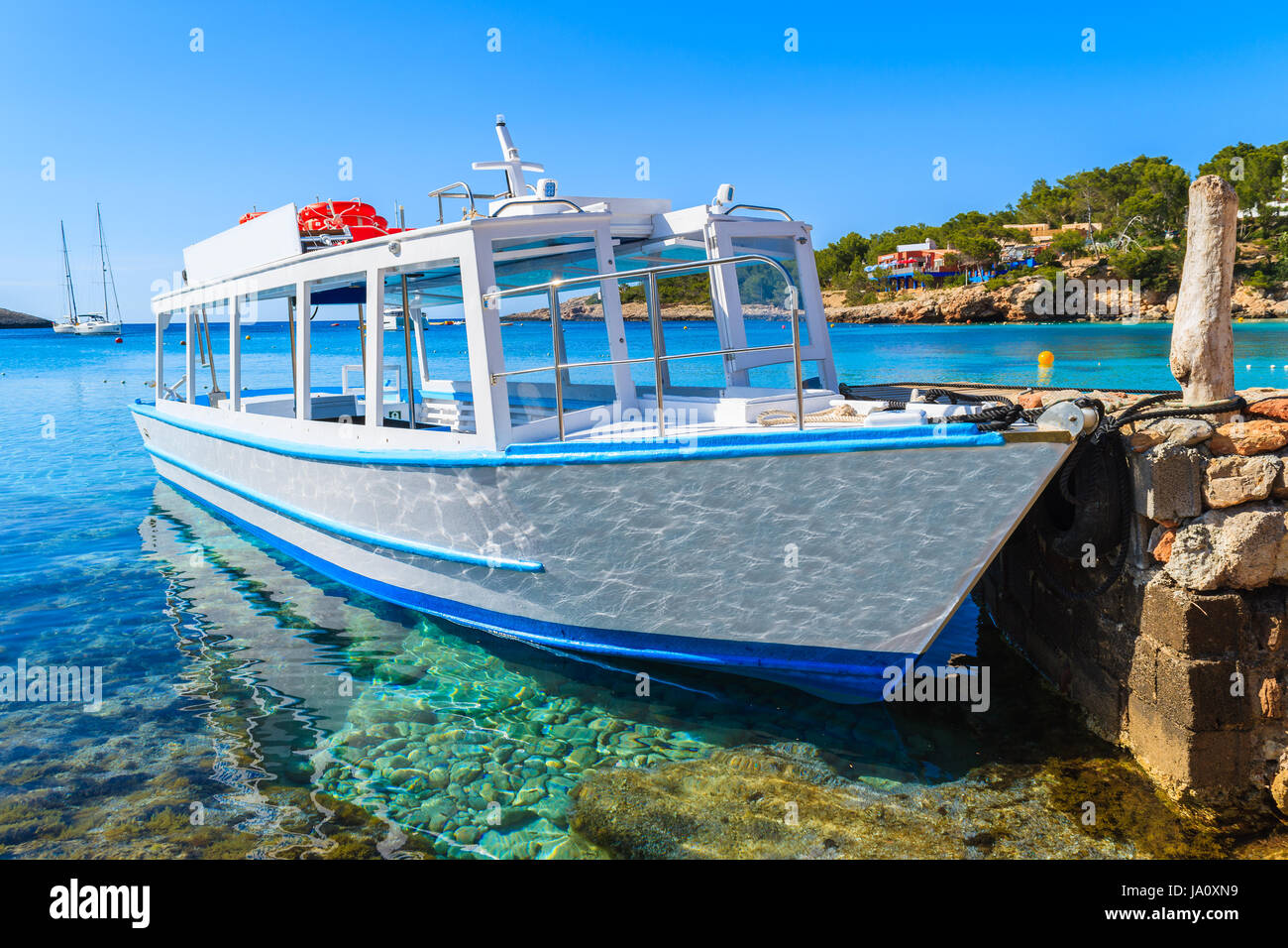 White and blue colour ferry boat for tourists mooring in Cala Portinatx ...