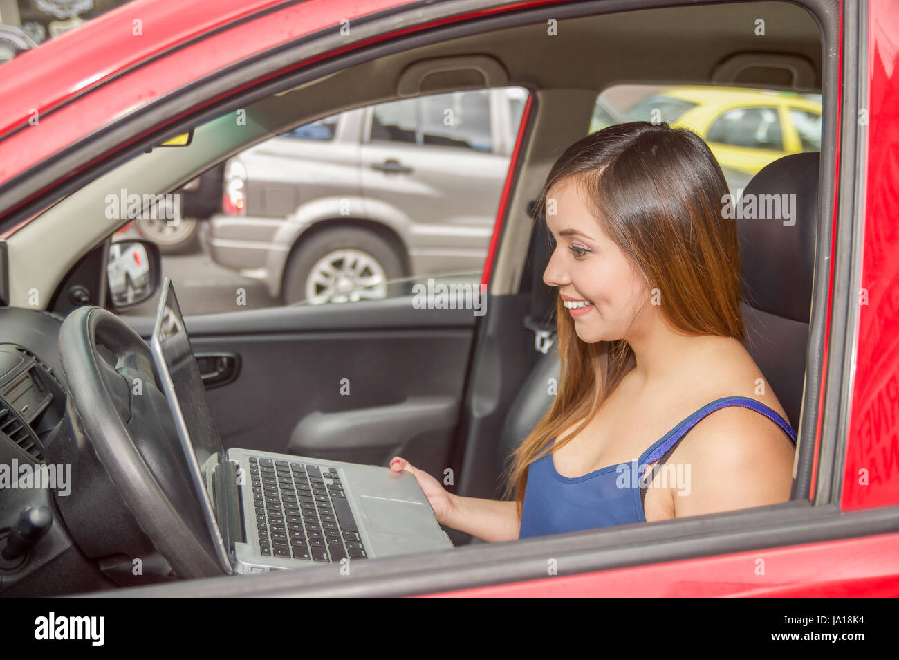 Beautiful smiling young lady working in her computer, while the car ...
