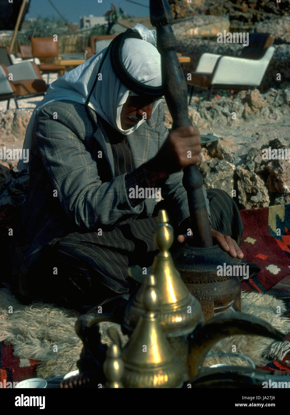 Arab pounding coffee beans using a wooden pestle and mortar, Jordan ...